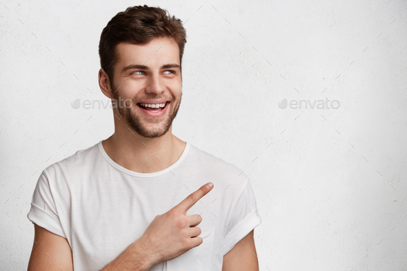 Confident positive male model has appealing smile, looks with joyful ...
