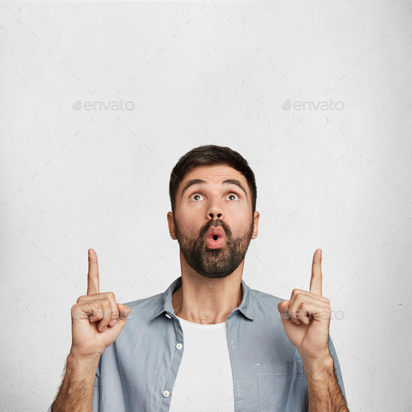 Vertical shot of amazed embarrassed male has stubble, dressed in ...