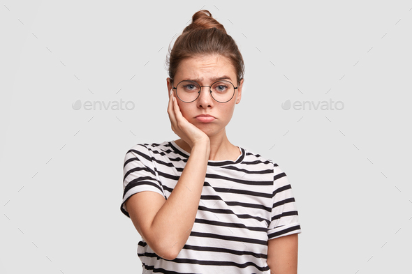 Photo of serious unhappy European female keeps hand on cheek, has ...