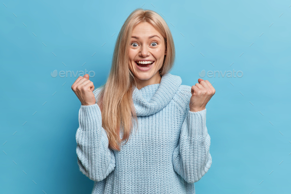 Successful positive female model stands empowered and clenches fists ...