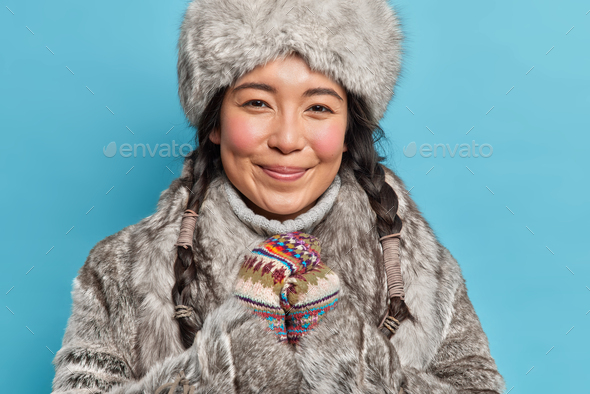 Smiling northern woman with dark hair keeps hands together has ...