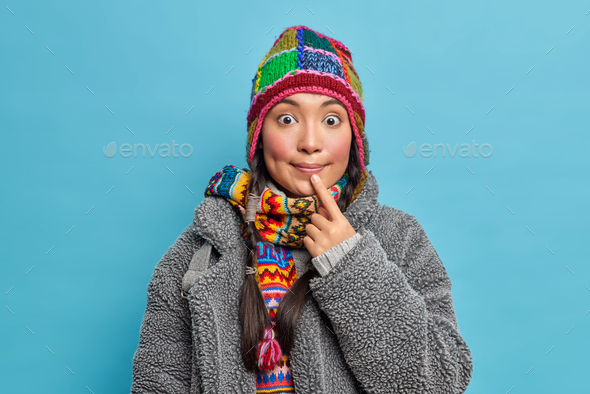 Wondered ethnic girl looks surprisingly at camera keeps index finger ...