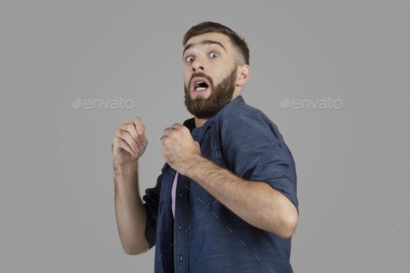 Young hipster guy being scared or terrified over grey studio background ...
