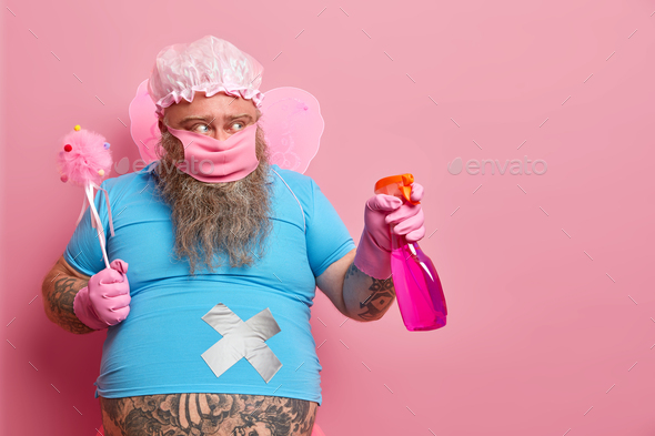 Stout bearded man has fun and pretends to be fairy of cleanliness wears ...