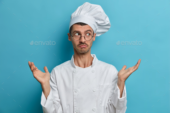 Confused unaware man chef raises hands and shrugs shoulders dressed in ...