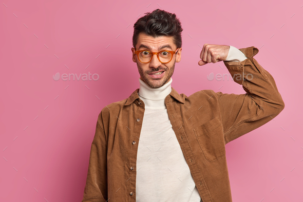 Horizontal shot of young man with dark hair raises arm being very ...