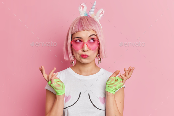 Hesitant thoughtful Asian woman raises hands has confused face ...