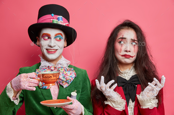Smiling happy hatter from wonderland wears bright makeup drinks tea at ...