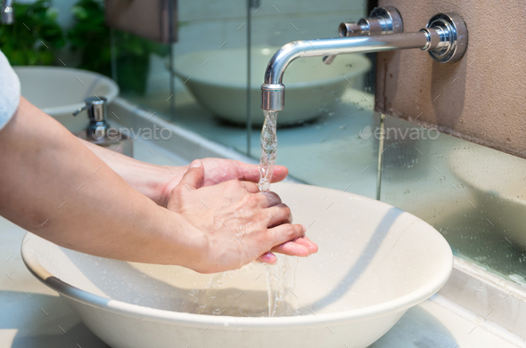 Hand washing with Chrome faucet over the washbasin in modern bathroom ...