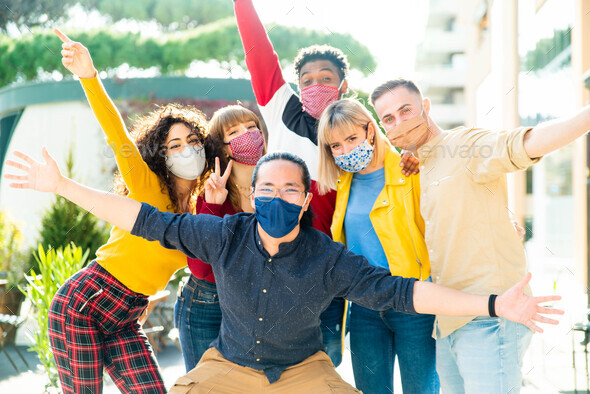 Group of multiracial people wearing protective face masks smiling at ...