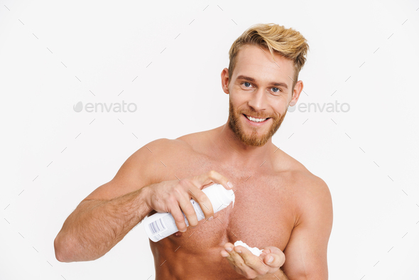 Joyful caucasian shirtless man smiling while using shaving foam Stock Photo by vadymvdrobot