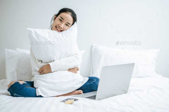 The woman sitting on the bed and hugging laptop. Stock Photo by Johnstocker