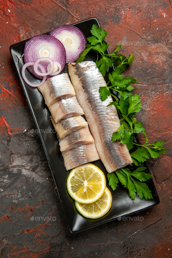 top view fresh sliced fish with greens and onion inside black pan on ...