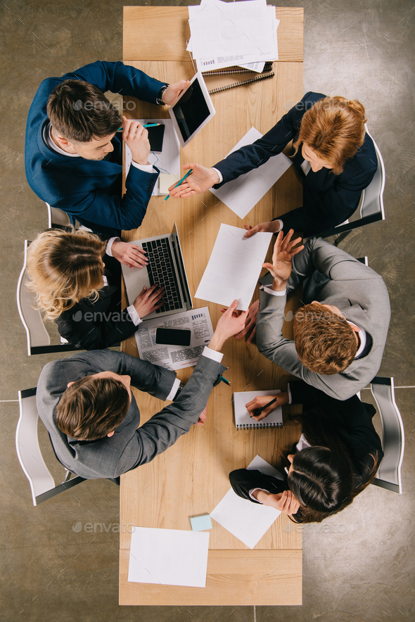 Top view of businesspeople working at table with documents, laptop ...