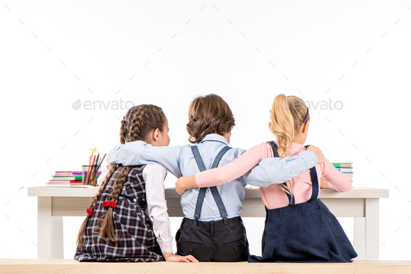 Back view of classmates sitting at desk with books and hugging Stock ...