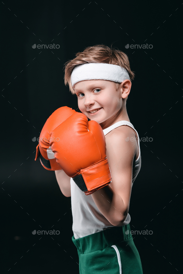 smiling boy in boxing gloves isolated on black, active kids concept ...