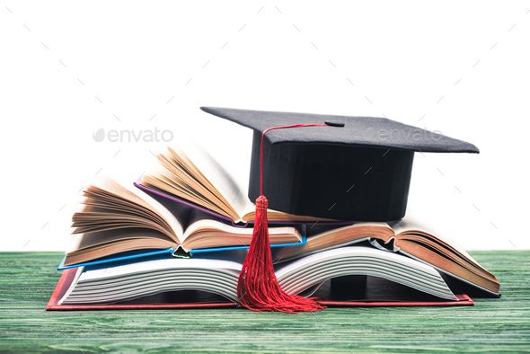 Graduation cap on stack of open books Stock Photo by LightFieldStudios
