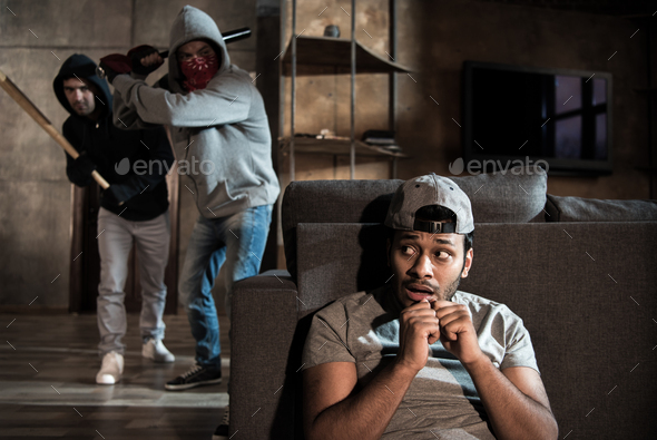 Scared man hiding behind sofa from burglars, house robbery scene Stock ...