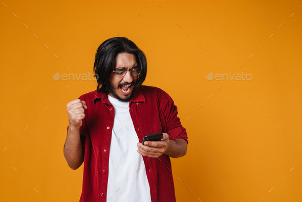 Happy young indian man using mobile phone isolated Stock Photo by vadymvdrobot