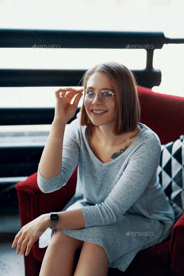 Attractive girl sitting in a red cozy chair Stock Photo by diignat