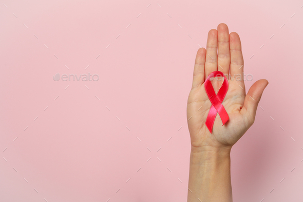 Female hand with pink awareness ribbon on pink background Stock Photo ...