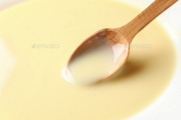 Wooden spoon in condensed milk, close up Stock Photo by AtlasComposer