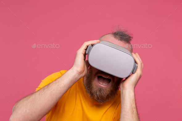 Portrait of scared gamer, man with beard in t-shirt wearing vr glasses ...