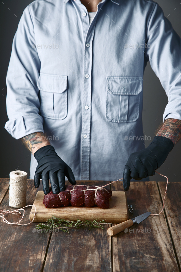 Butcher ties meat with rope to smoke , on table with species Stock ...