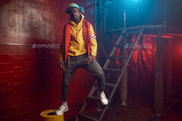 Stylish rapper poses on stairs in grunge studio Stock Photo by NomadSoul1