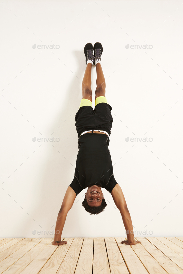 Smiling African American athlete doing handstand Stock Photo by bublikhaus