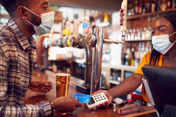Male Customer Wearing Mask In Bar Making Contactless Payment For Drinks ...