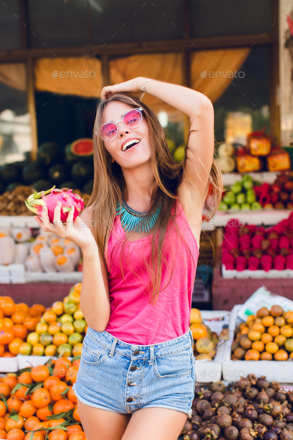 Brightful girl with long hair is posing to camera on market with ...