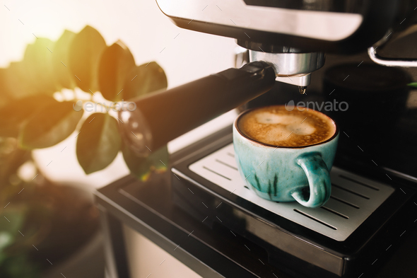 Green cup of coffee at the coffee maker machine, coffee time. Blurred ...