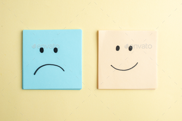 Close up view of sad and smiling emoji faces on small note sheets on ...