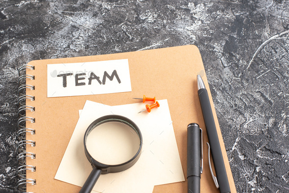 above view team note attached to notepad with magnifier and pens on ...