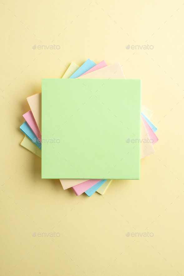 Overhead view of stacked sticky note cubes on shaded yellow background ...