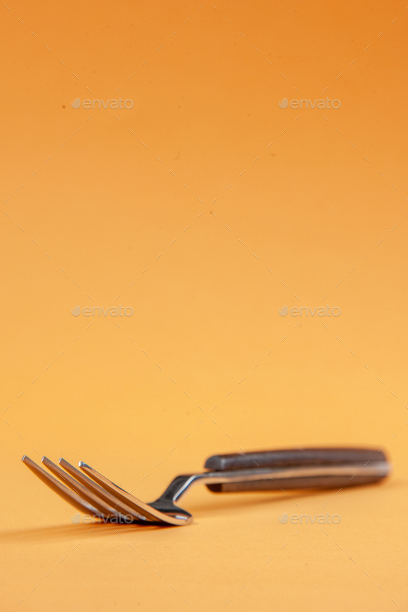 Vertical view of elegant metal fork on golden background with free ...