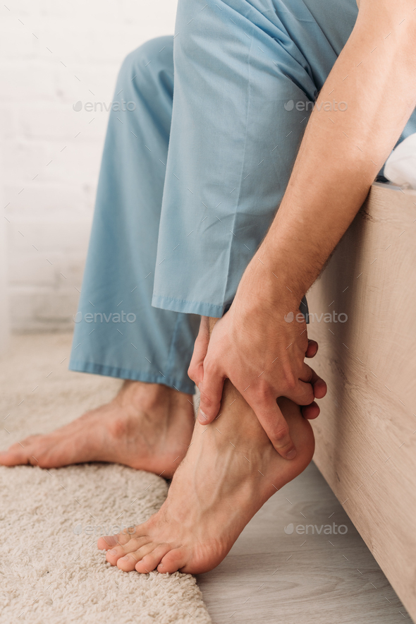 cropped view of man touching leg while suffering from pain in Achilles ...