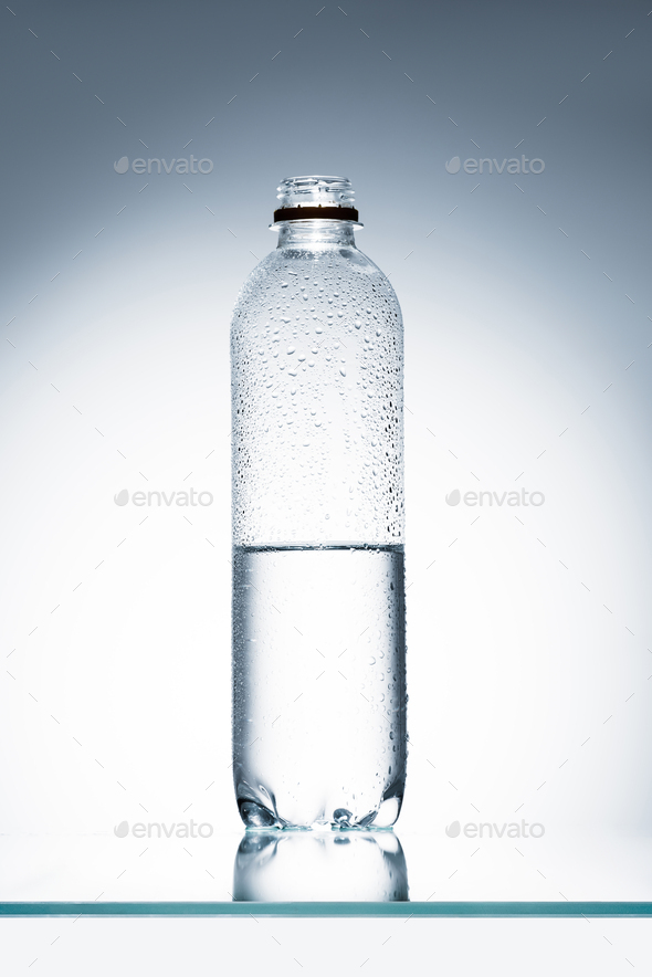 half full plastic bottle of water on reflective surface Stock Photo by ...
