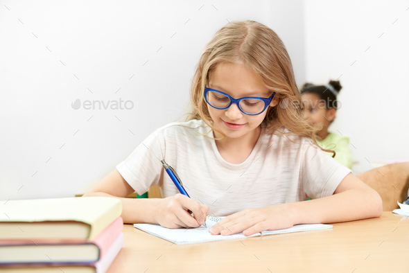 Front view of studious girl doing task on lesson in school Stock Photo ...