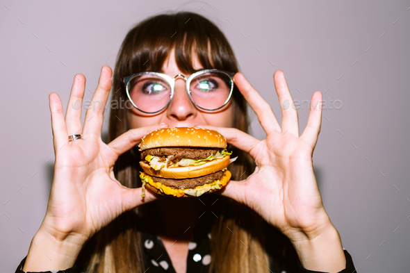 Indoor bright flash image of woman eating big junky burger, Stock Photo ...