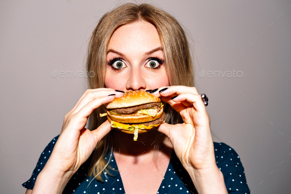 Indoor bright flash image of woman eating big junky burger, Stock Photo ...