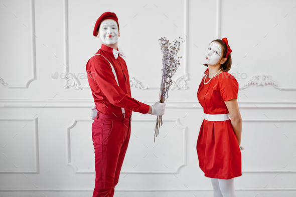 Mime artists in red costumes, scene with bouquet Stock Photo by NomadSoul1