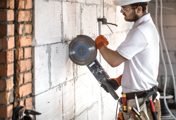 The industrial Builder works with a professional angle grinder to cut ...
