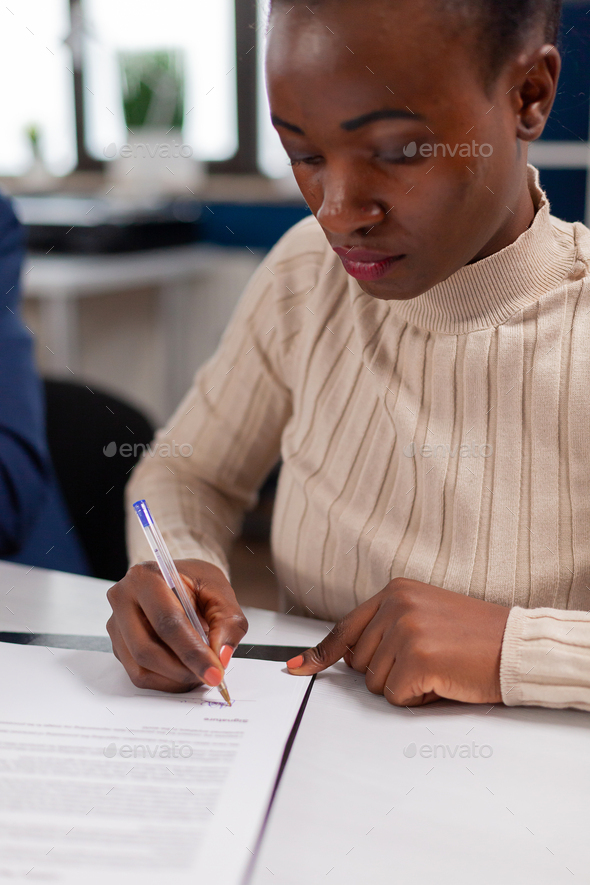 African businesswoman reading signing documents Stock Photo by DC_Studio