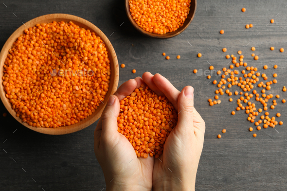 Female hands holds red legumes over a dark background with bowls of ...