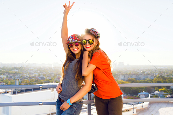 Outdoor lifestyle portrait of two best fiends sisters girls posing on ...