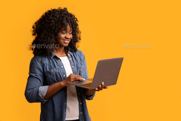 Pretty black lady using laptop on yellow background Stock Photo by ...