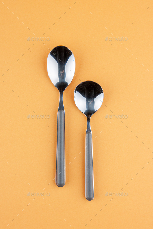Overheadd view of stainless teaspoons lying side by side on golden ...