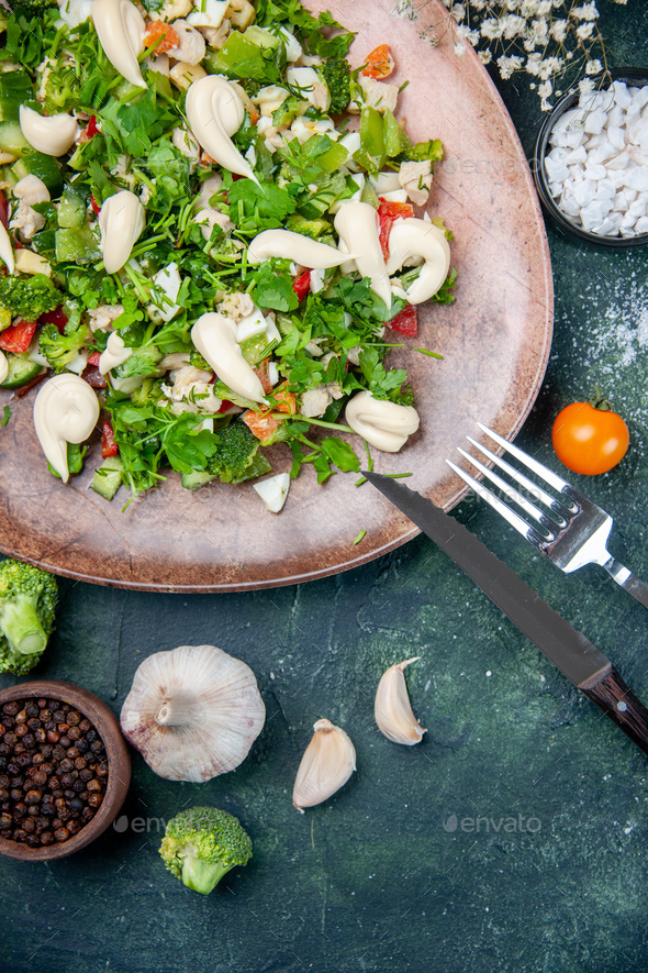 top view vegetable salad inside elegant plate with cutlery on dark-blue ...